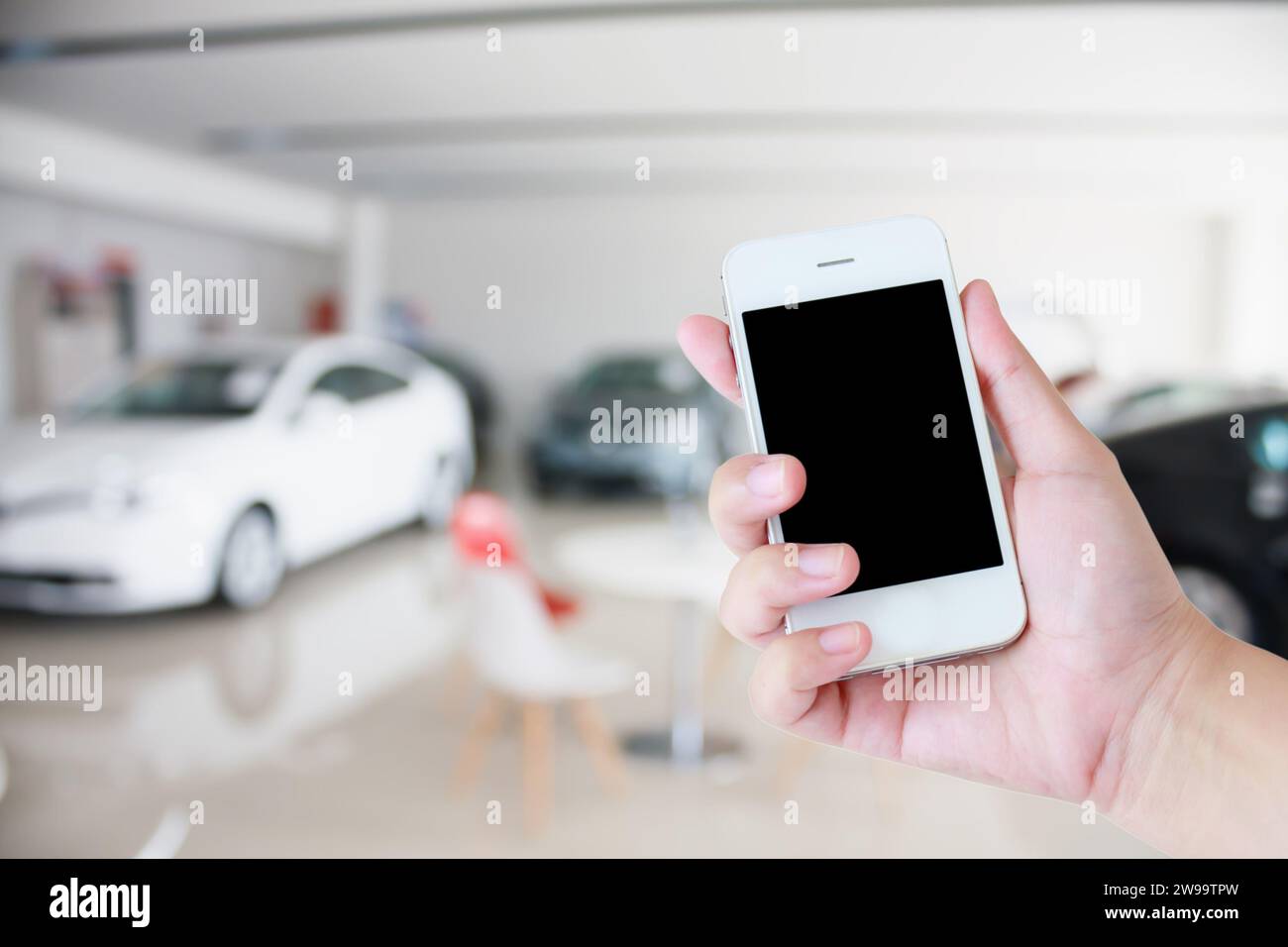 hands holding mobile phone with new cars in showroom dealership Stock ...