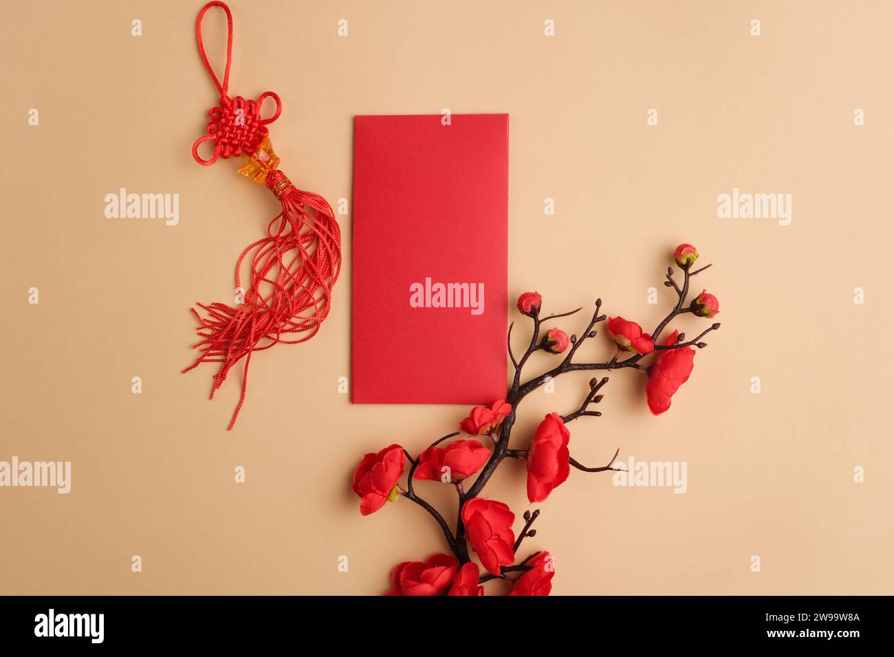 A red envelope, a peach blossom branch and a decorative string are ...
