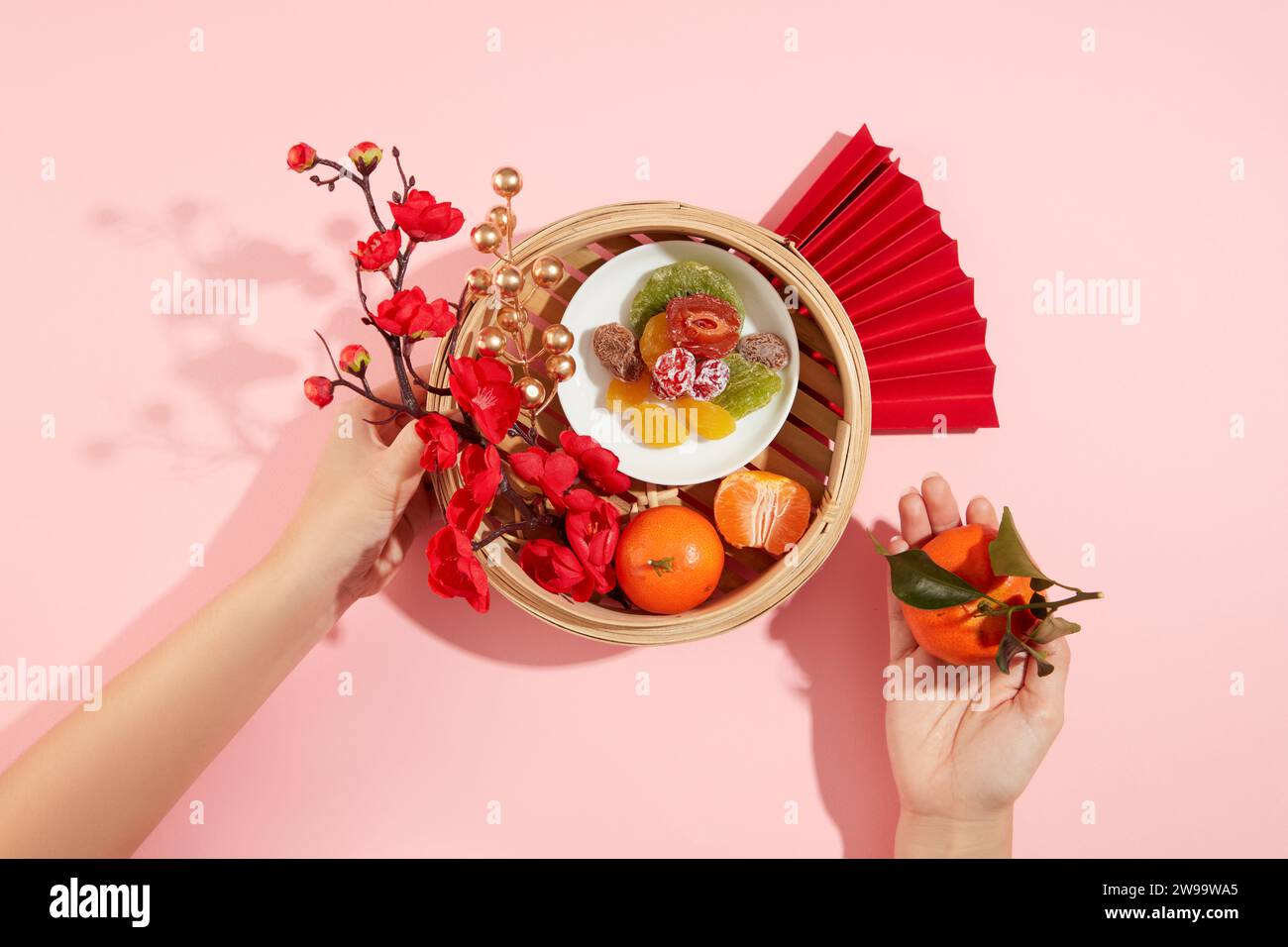 The hand is holding a bamboo steamer, inside there is a branch of red ...