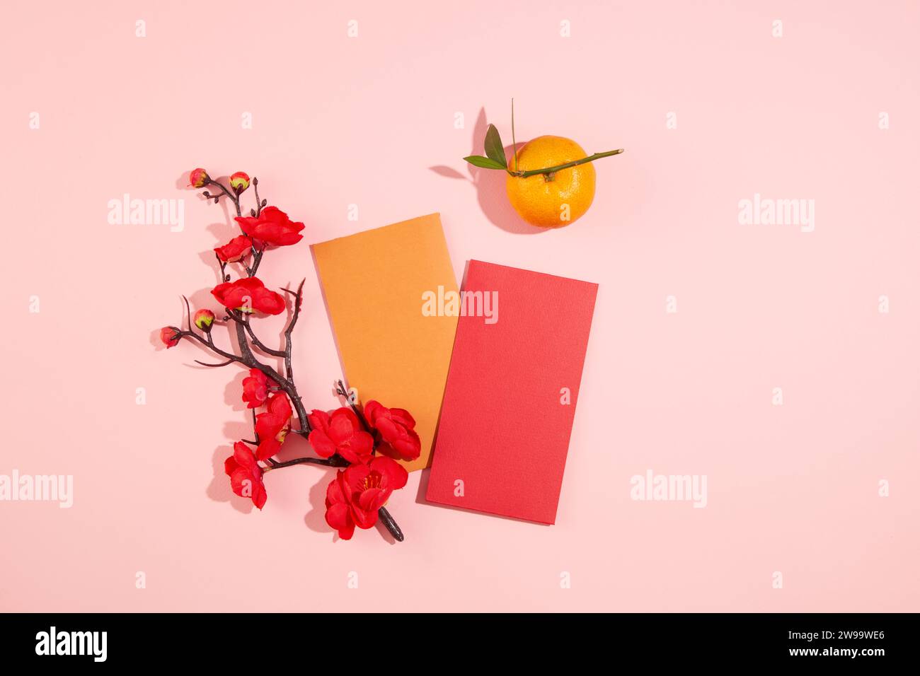 A peach blossom branch, two lucky money envelopes and a tangerine are ...
