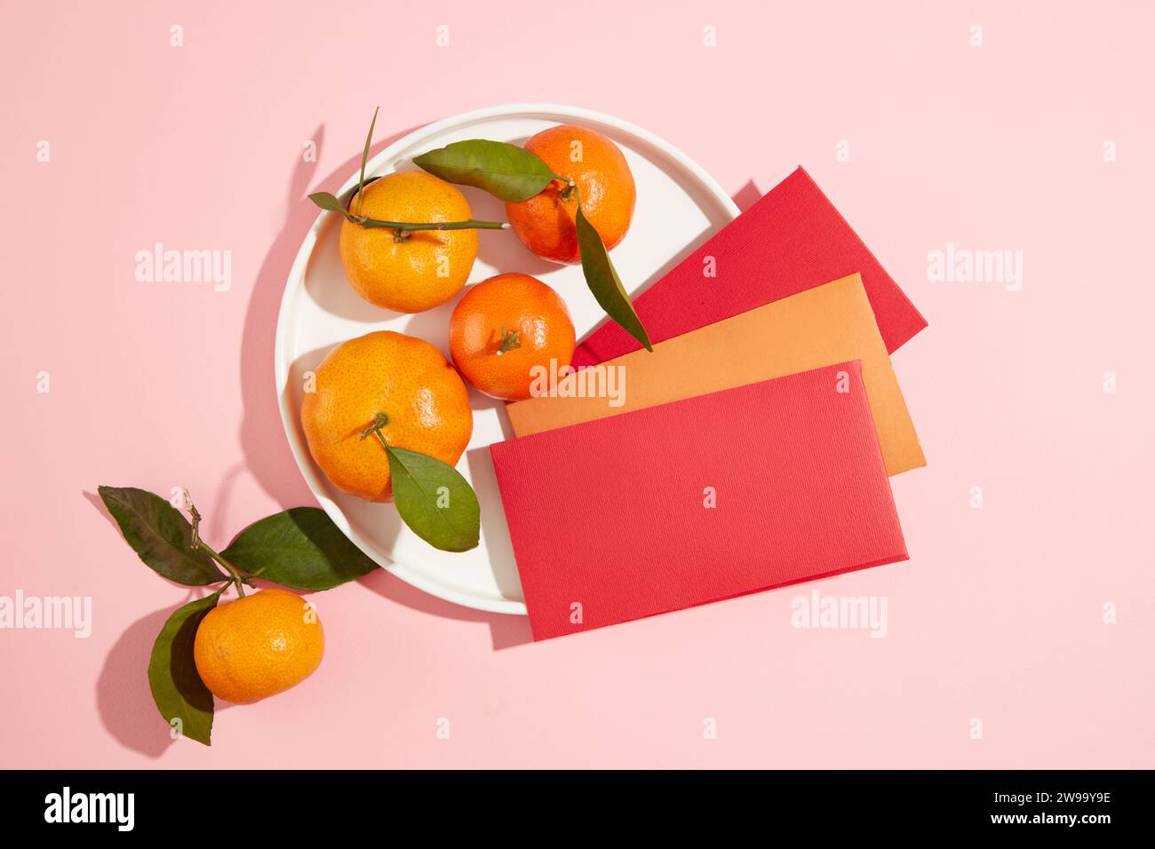Top view of three red envelopes displayed with a plate of tangerines on ...