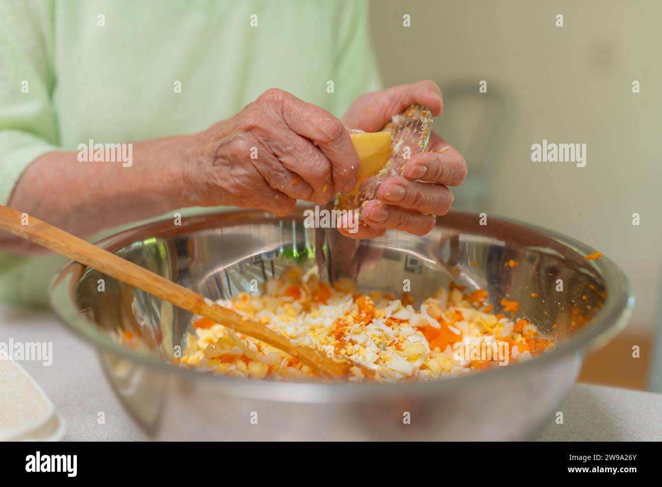 Old lady making a vegetable food in metal bowl. Cutting veggies for ...