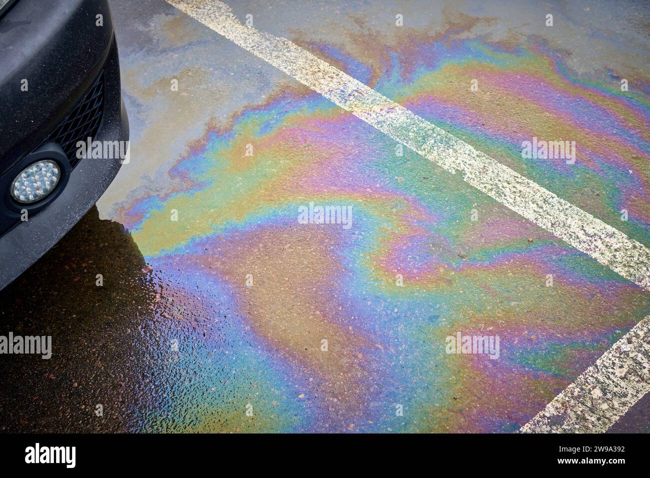 Multi-color patterns on the road from car's lubricating oil after the ...