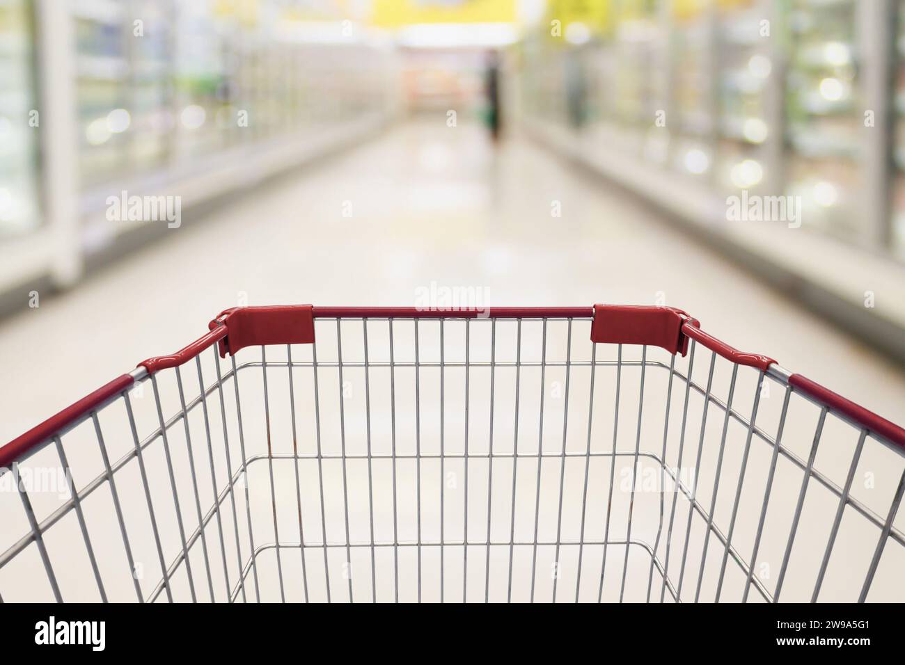 Empty red shopping cart view with milk and yogurt product shelves aisle ...