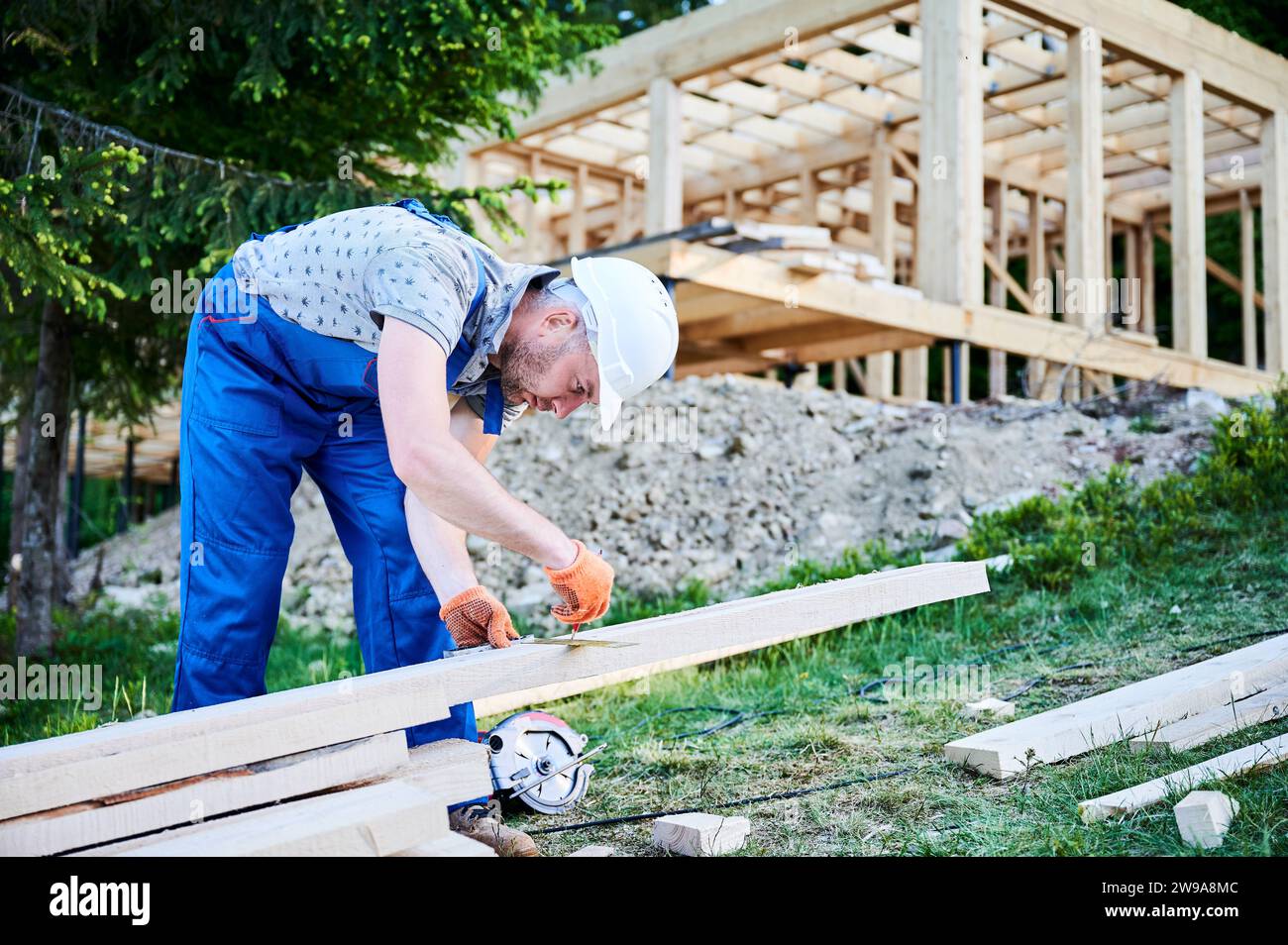 Carpenter constructing wooden-framed house. Man measures distances ...