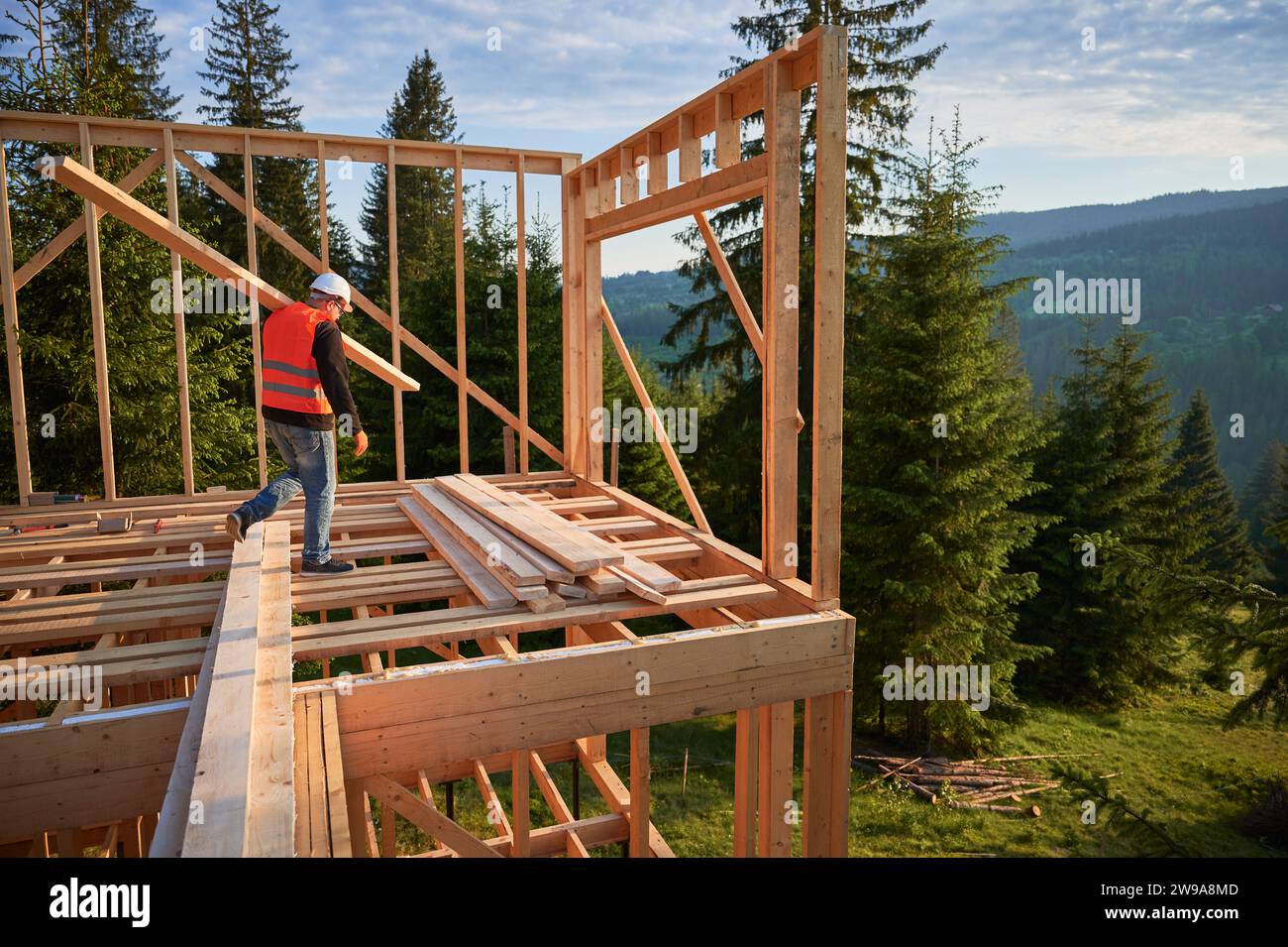Carpenter building wooden frame house near the forest. Man holding ...