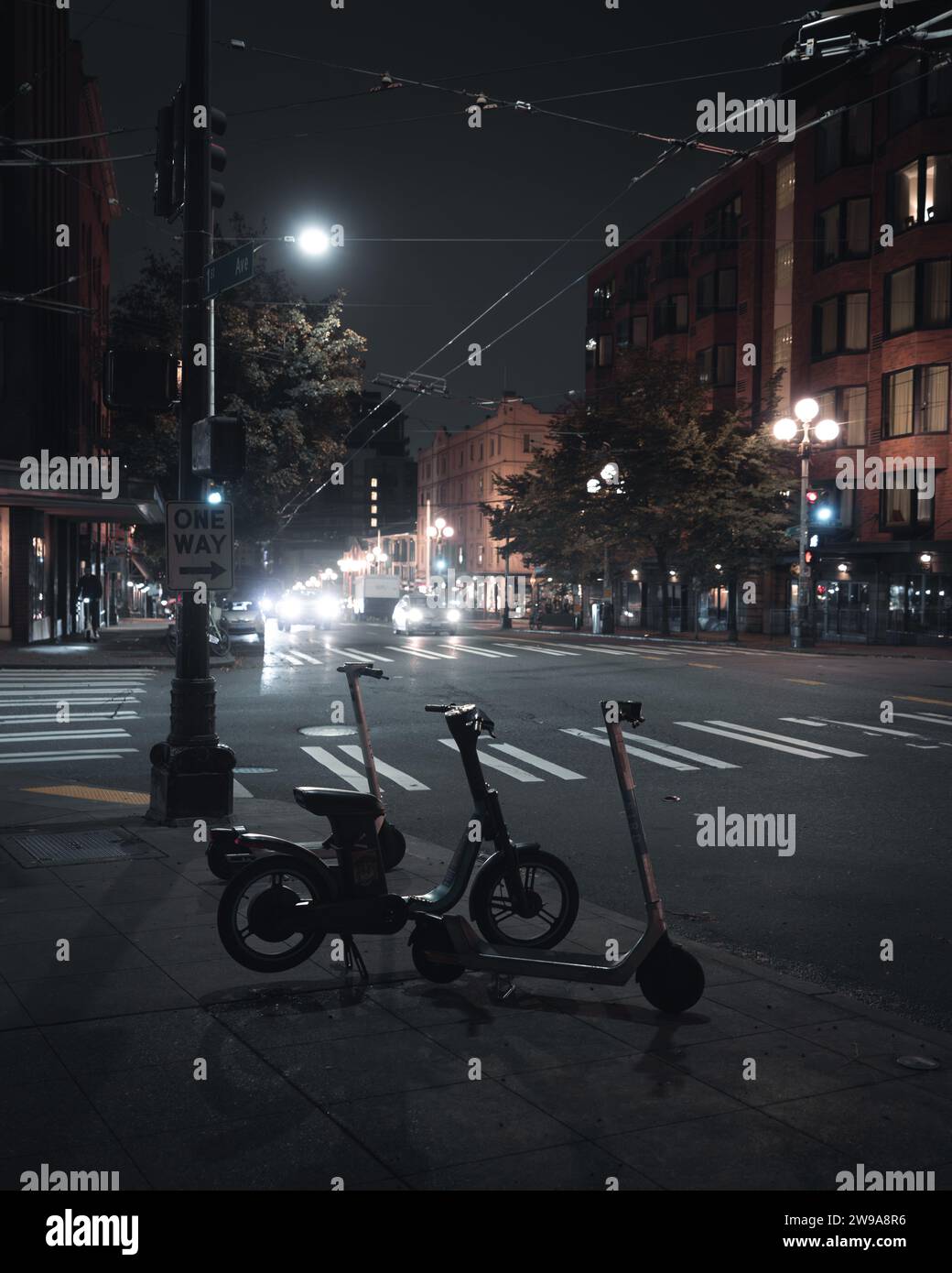 A vertical of motor scooters parked on a city street at night in ...