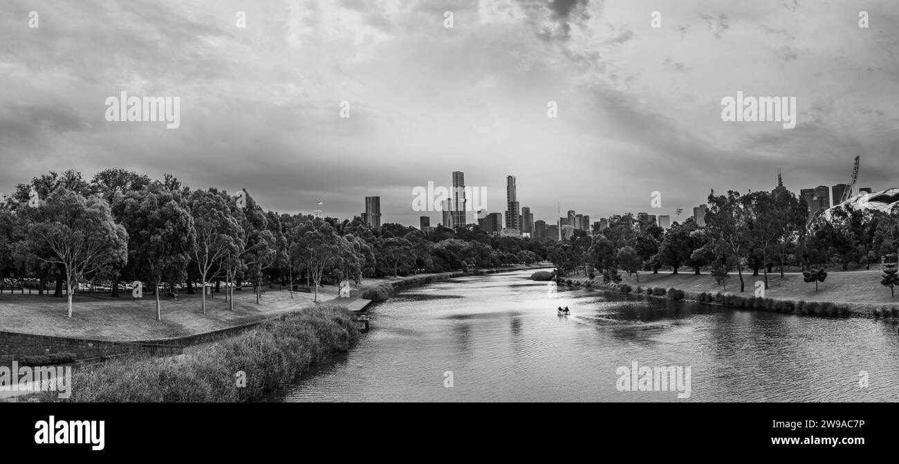 A grayscale of a river flowing through a modern city with skyscrapers ...