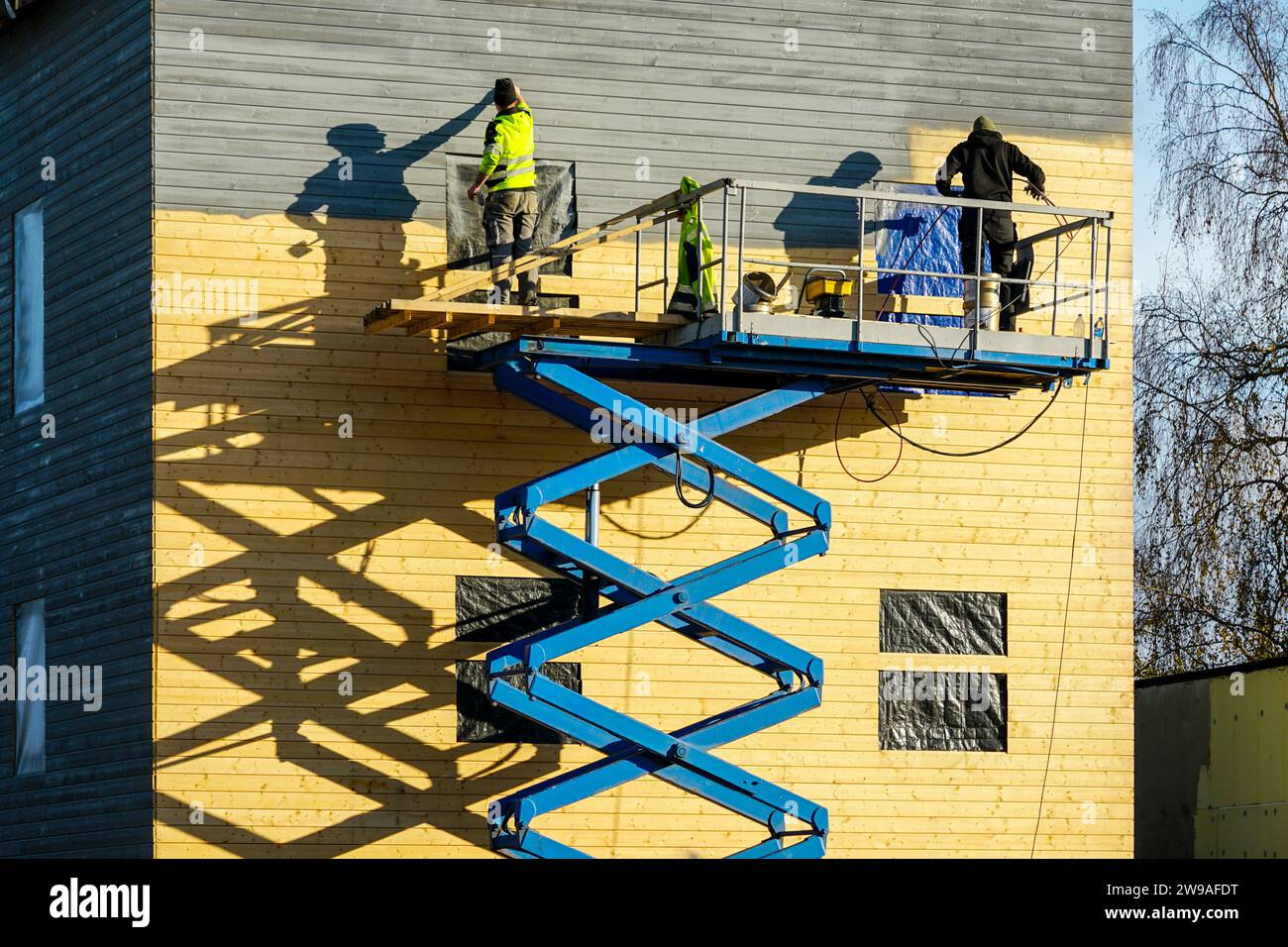 Residential house facade painting works after cladding with wooden ...