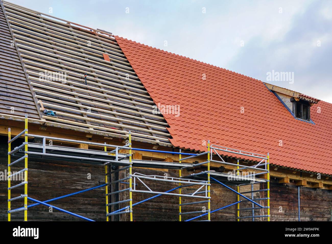 Installation of new clay tiles on new wooden battens on the roof of a ...