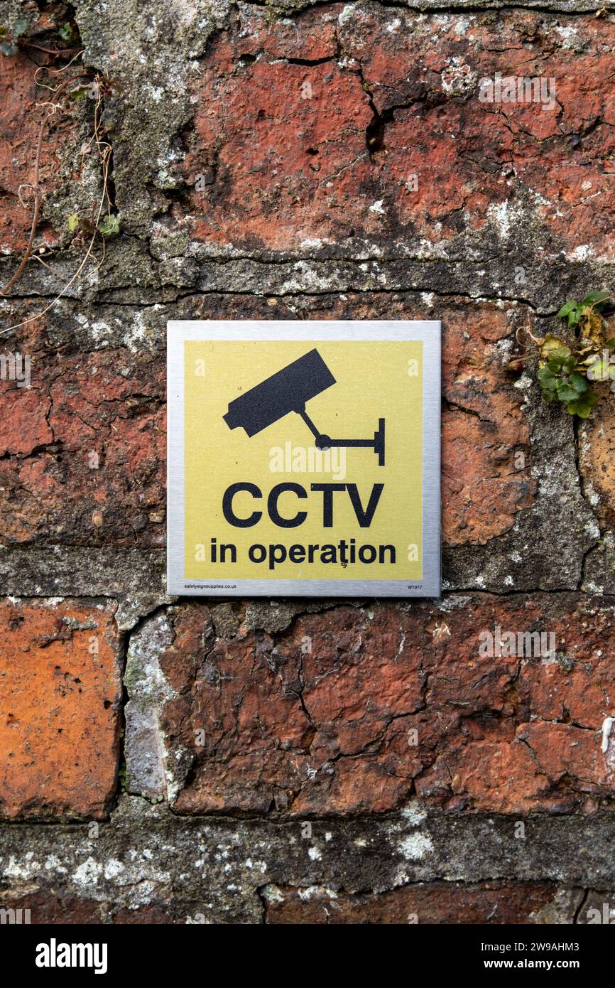 Yellow CCTV sign on a red brick wall Stock Photo - Alamy