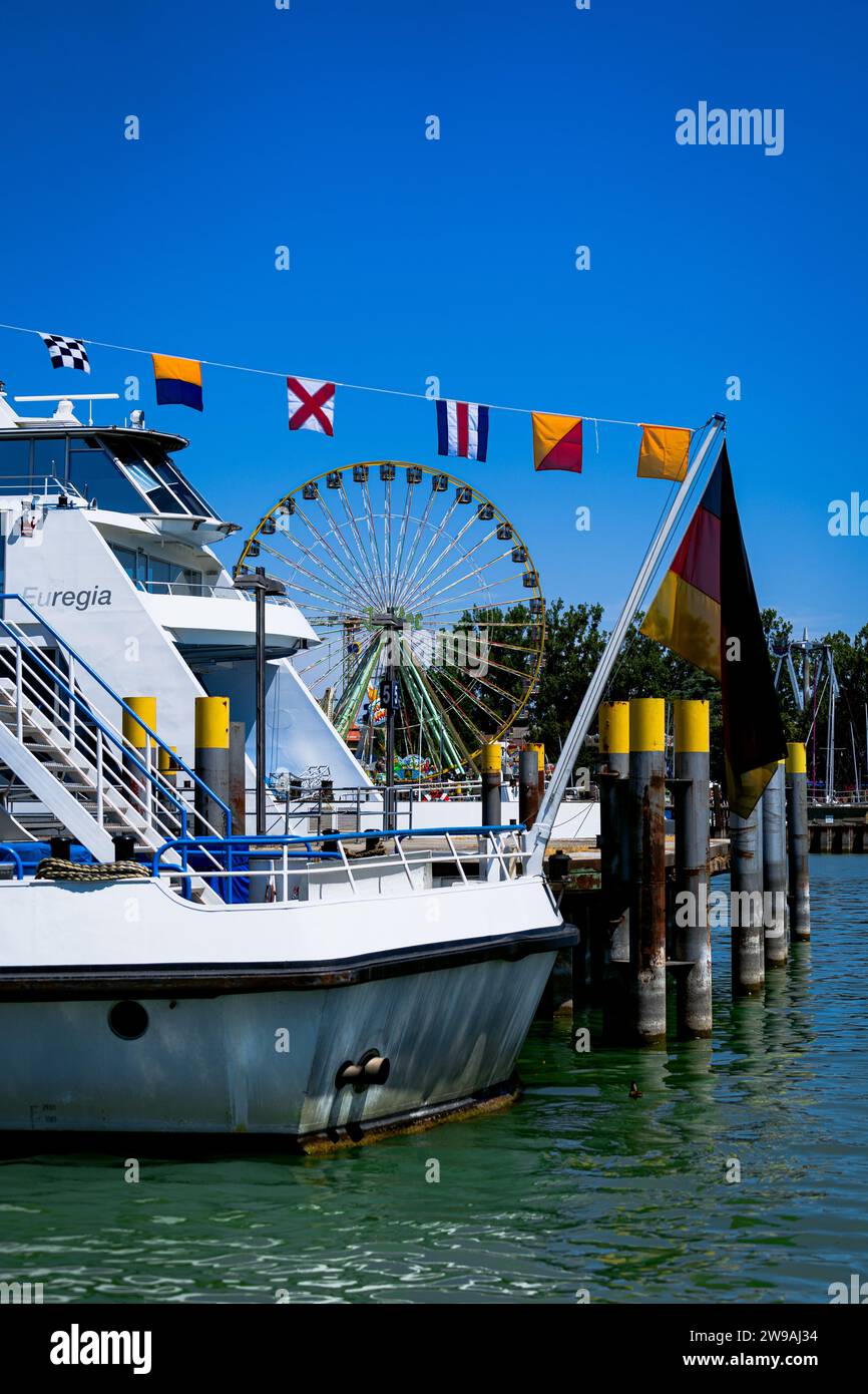The Ferris wheel on the shore of the lake. Tourist cruise ship anchored ...