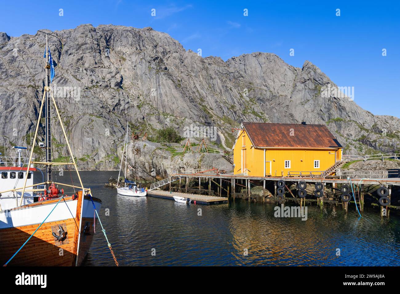 Nusfjord, Lofoten: Vibrant yellow fishing cabin and boats docked in a ...
