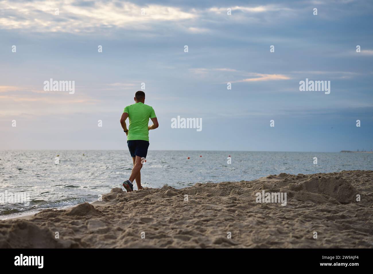 Back view of man jogging along sea beach at morning, Male athlete ...