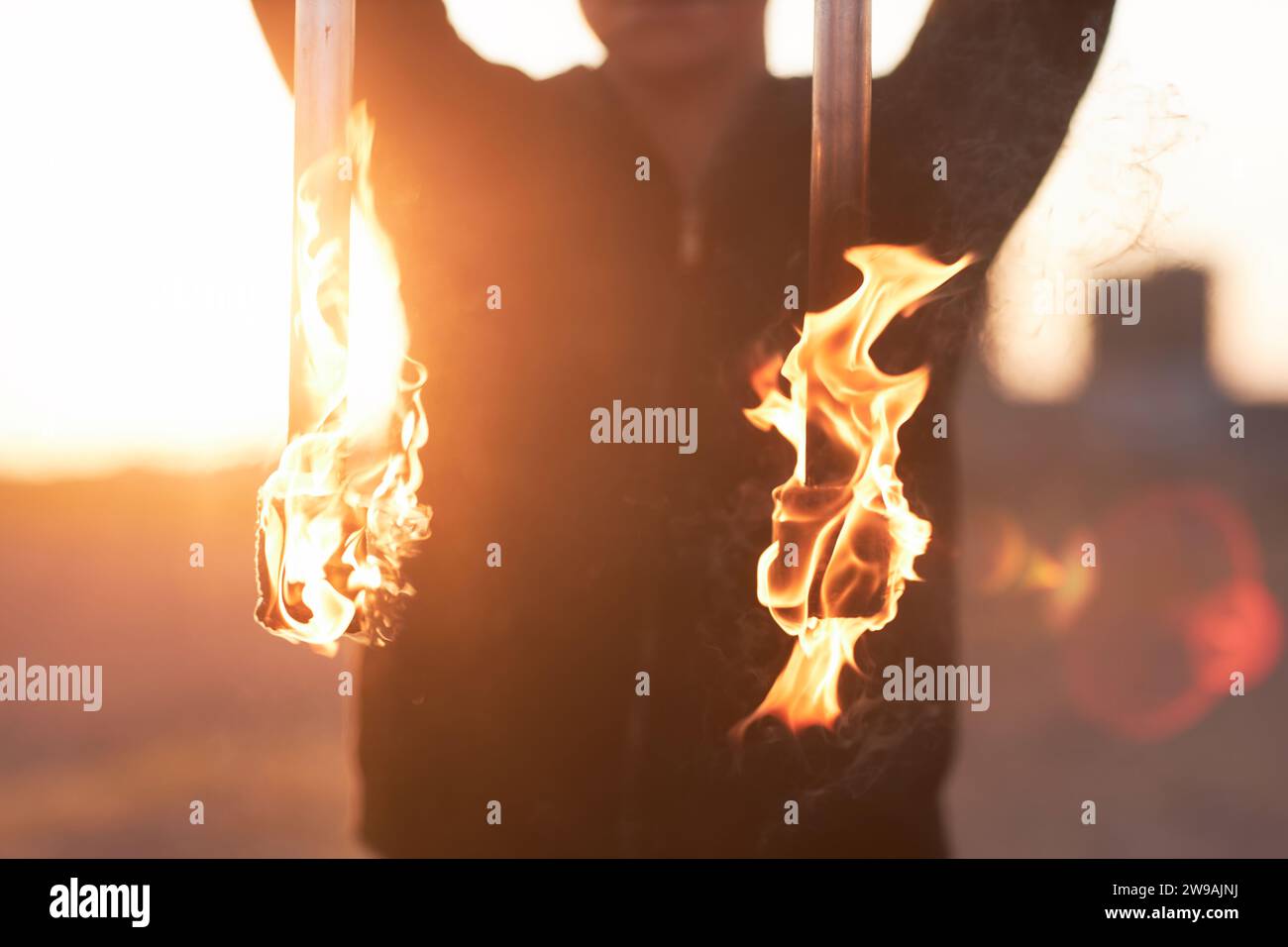 Close up of flaming fire rods with lens flare, unrecognizable fire show ...