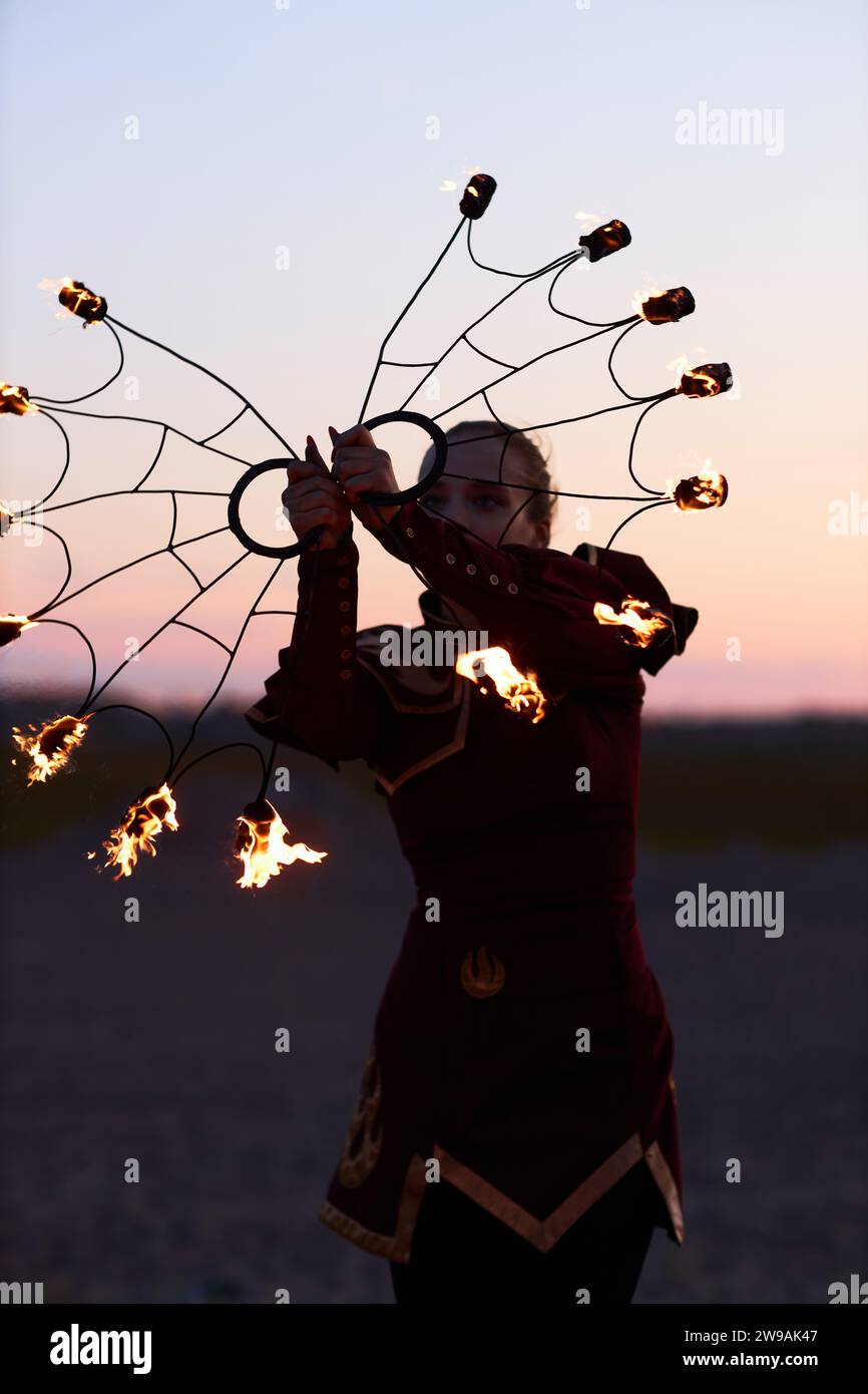 Vertical close up of female fire show performer dancing with flaming ...