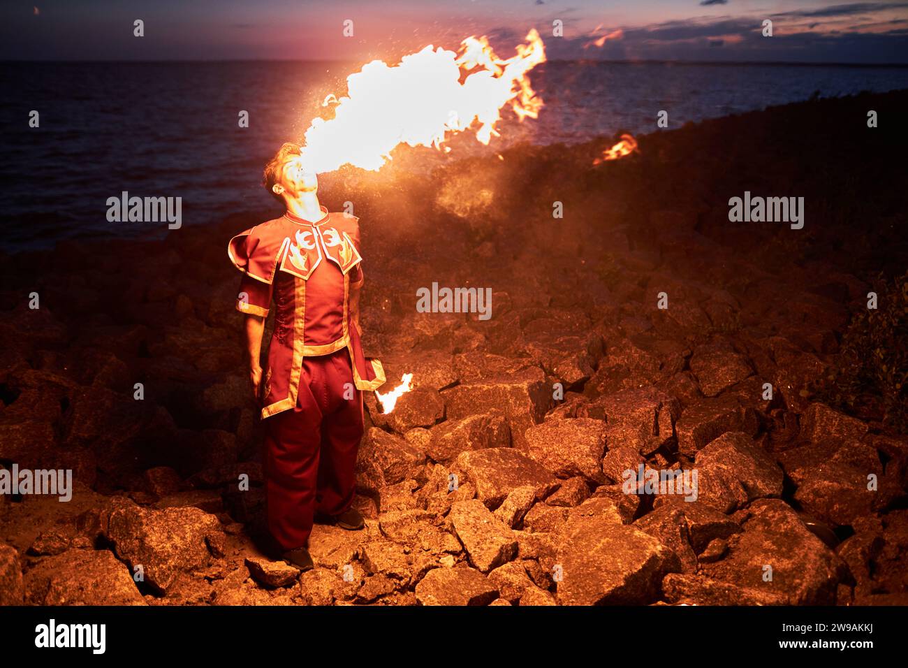 High angle portrait of young man breathing fire performing on beach ...