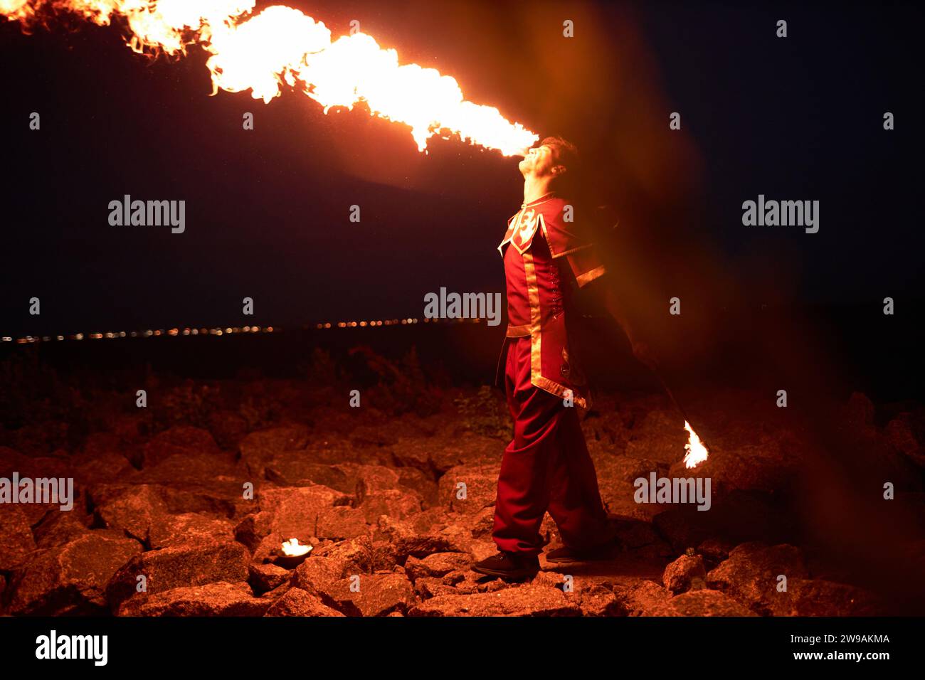 Side view portrait of young man breathing fire performing outdoors at ...