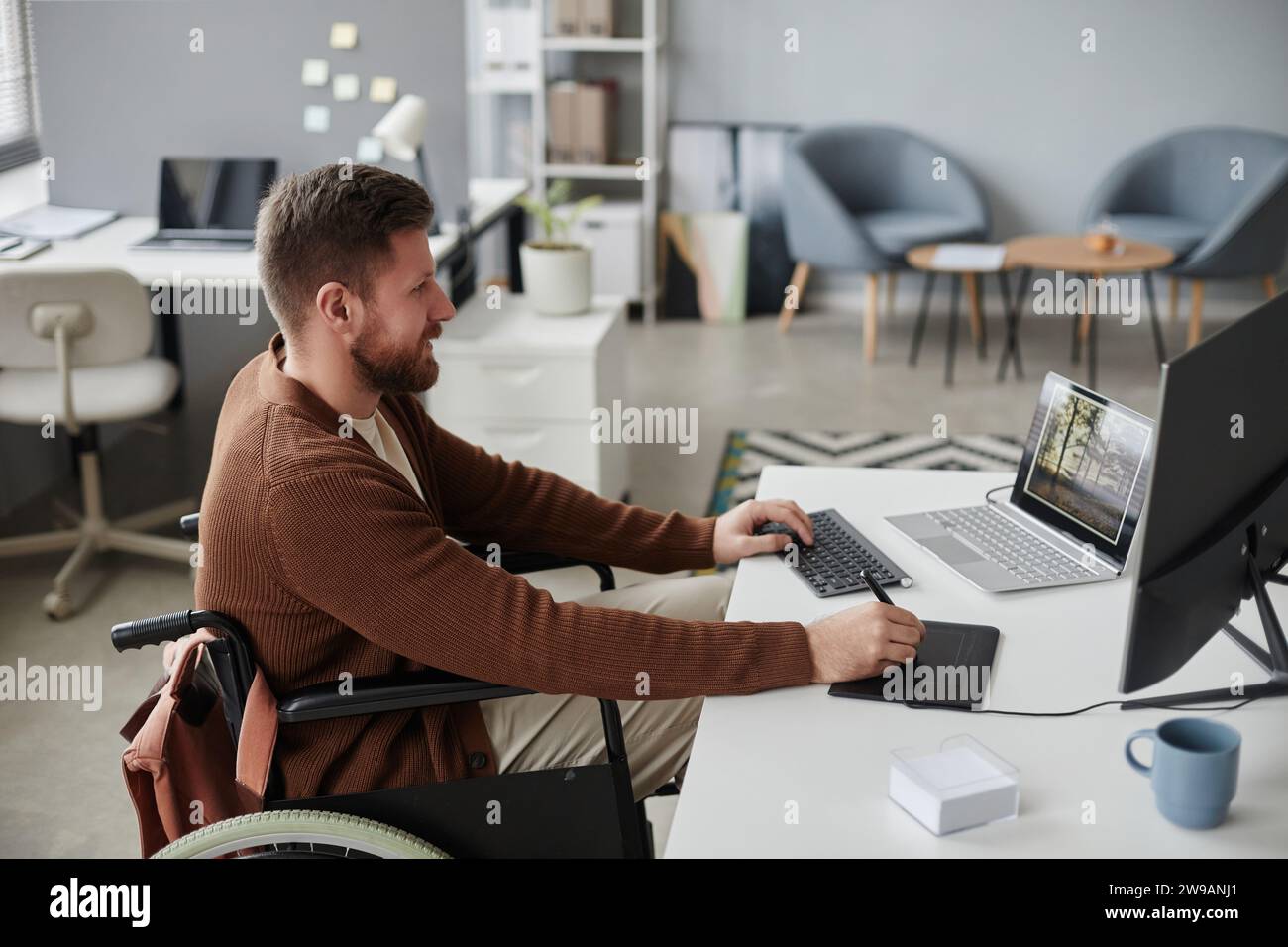 Side view portrait of man with disability editing photos or video at ...