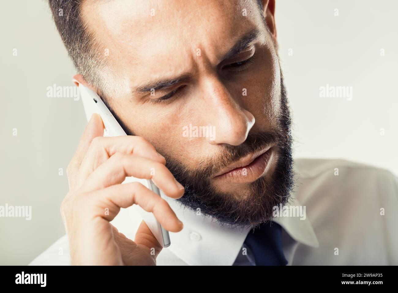 Man in business attire handles a tense call, his intense gaze ...
