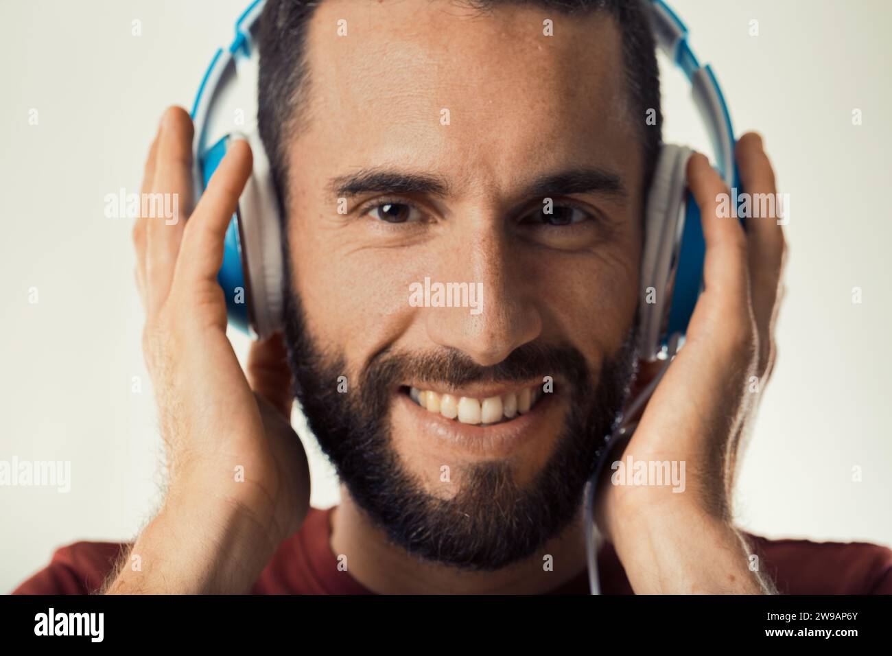Beaming man engaging with music via blue headphones exudes happiness ...
