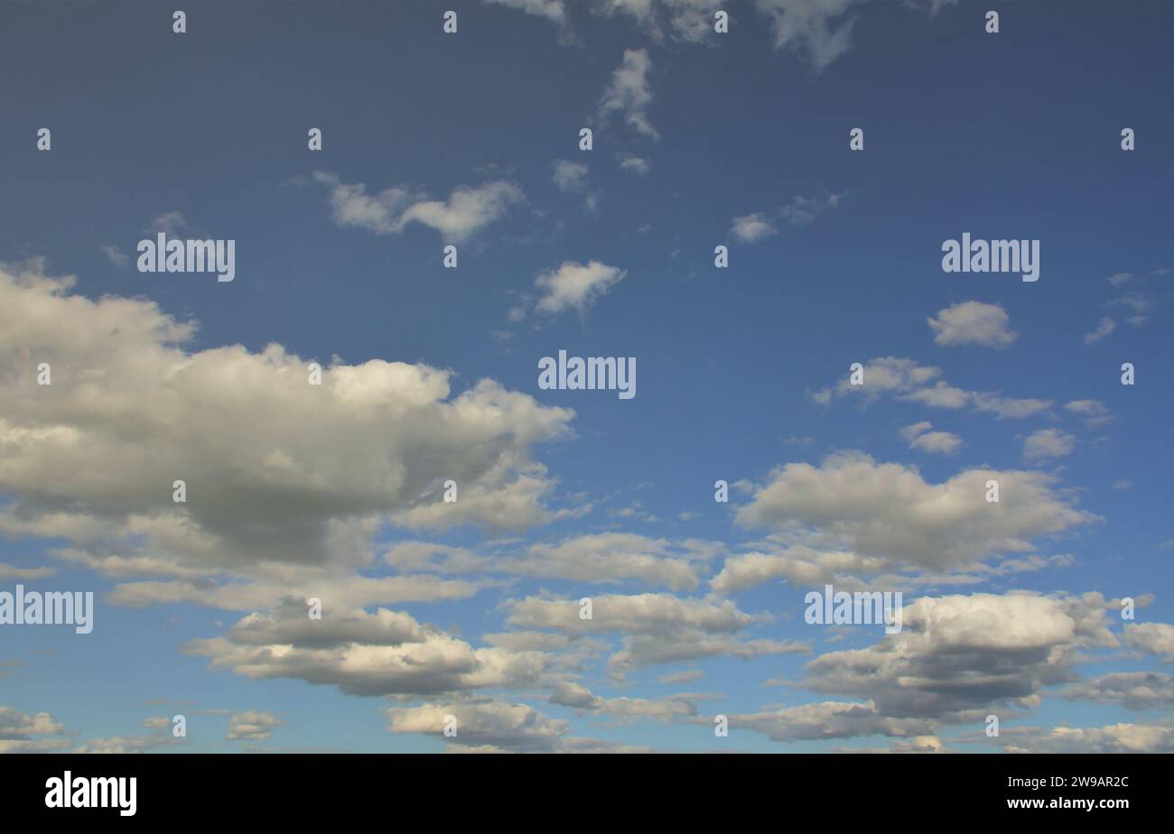 A blue cloudy sky with many small clouds blocking the sun Stock Photo ...