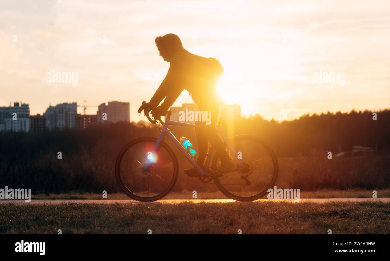 Silhouette of a cyclist riding bicycle on a dramatic sunset background ...