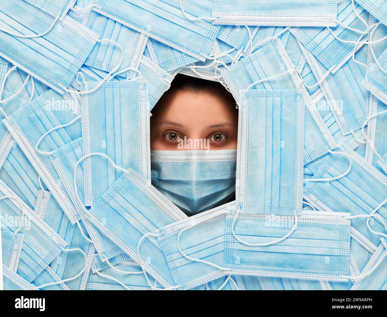 Young scared girl in surgical mask looks directly through a background ...