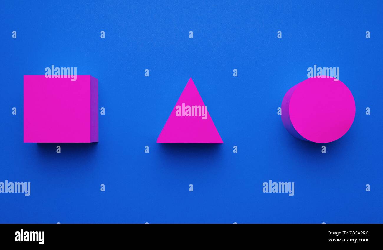 Magenta colored circle, triangle and square made of paper on blue ...