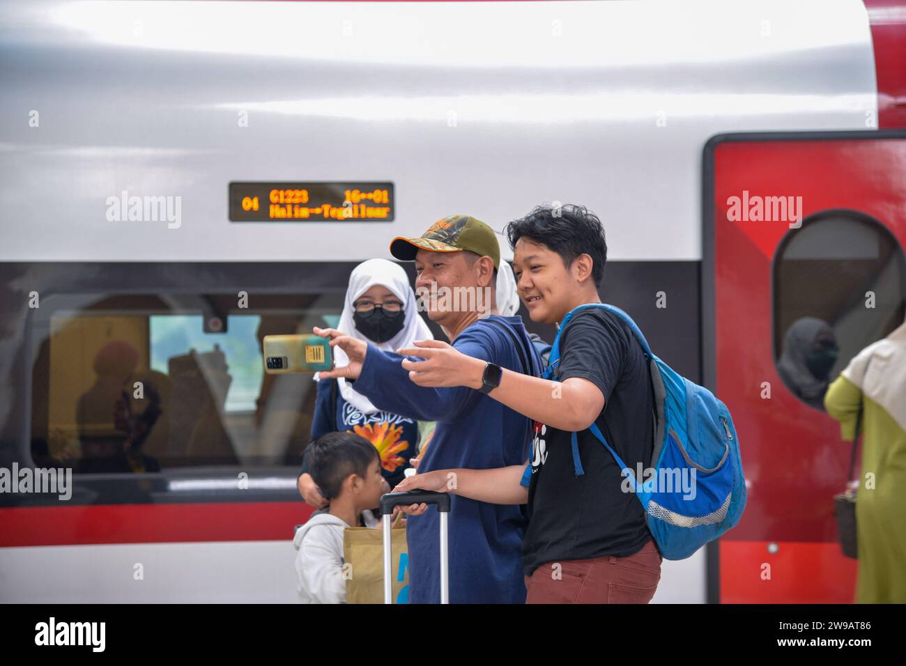 Jakarta, Indonesia. 25th Dec, 2023. Passengers pose for photos with a high-speed electrical ...