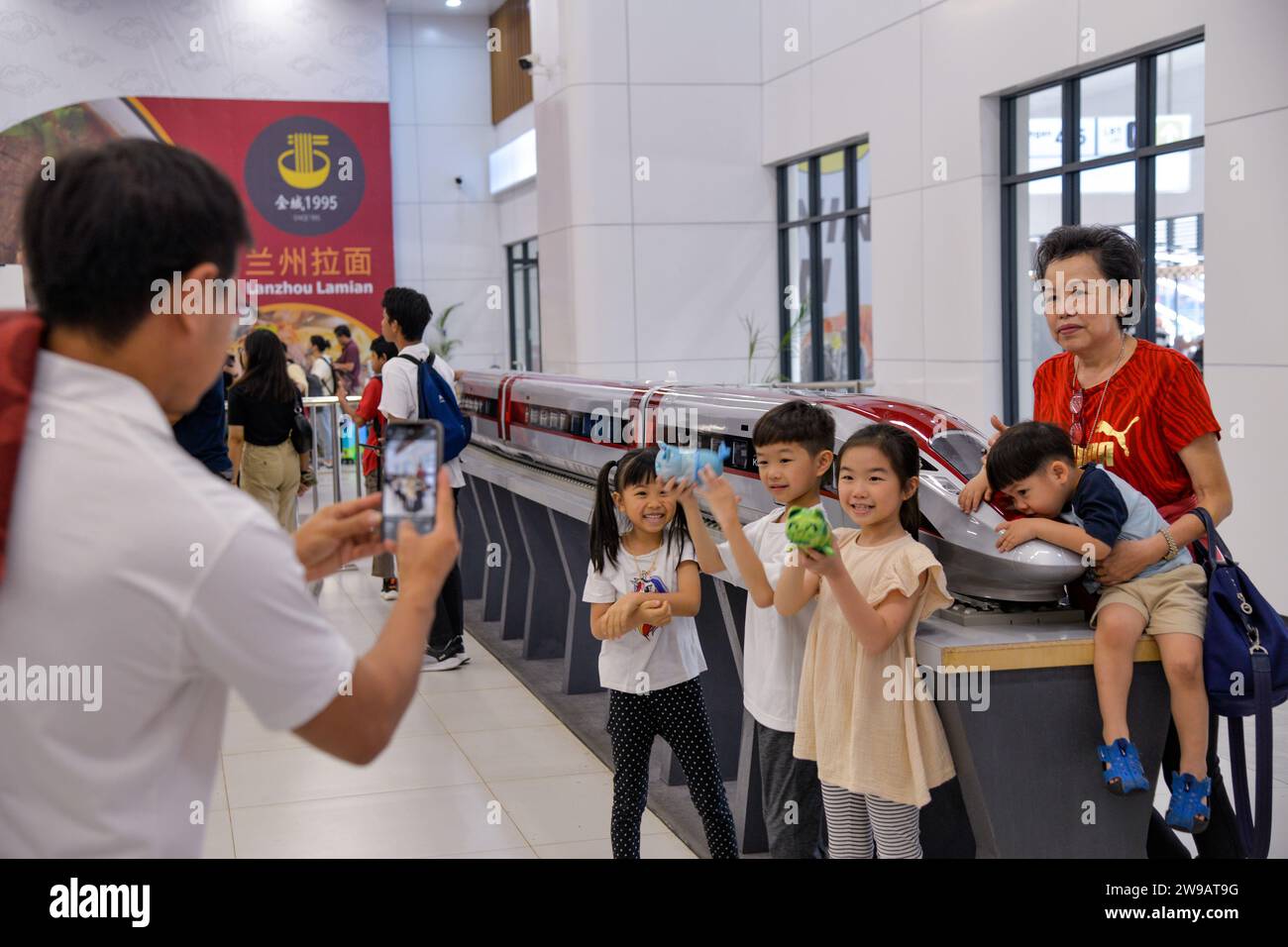 Jakarta, Indonesia. 25th Dec, 2023. People pose for photos with a model of a high-speed ...