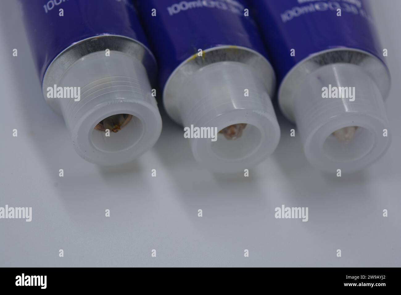 Three metal tubes of women's hair dye with large, clear, plastic lids ...