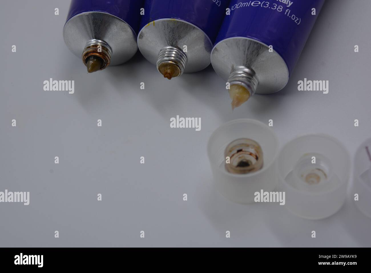 Three metal tubes of women's hair dye with large, clear, plastic lids ...