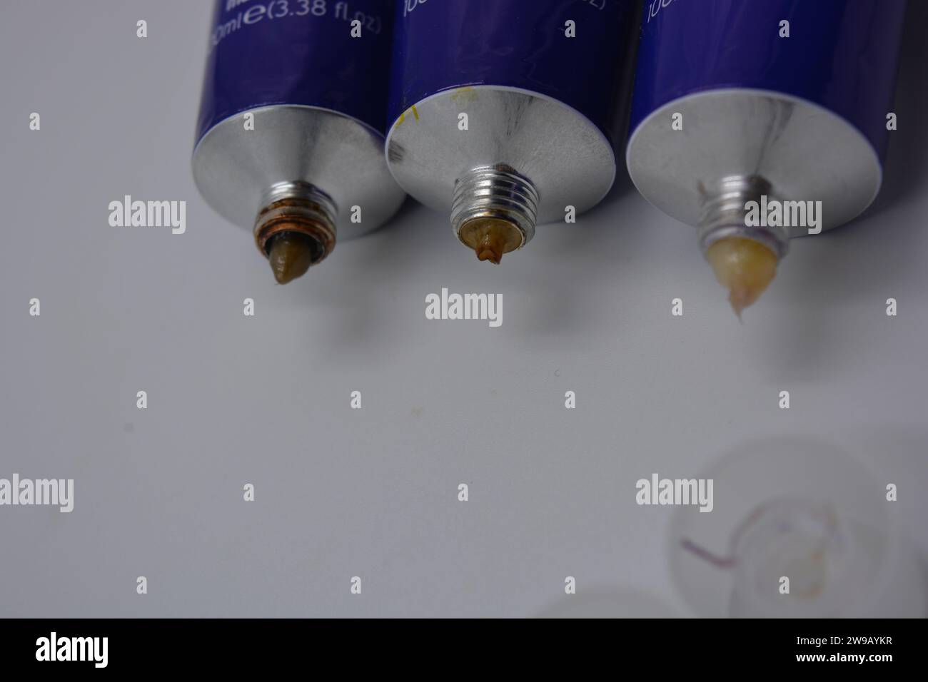 Three metal tubes of women's hair dye with large, clear, plastic lids ...