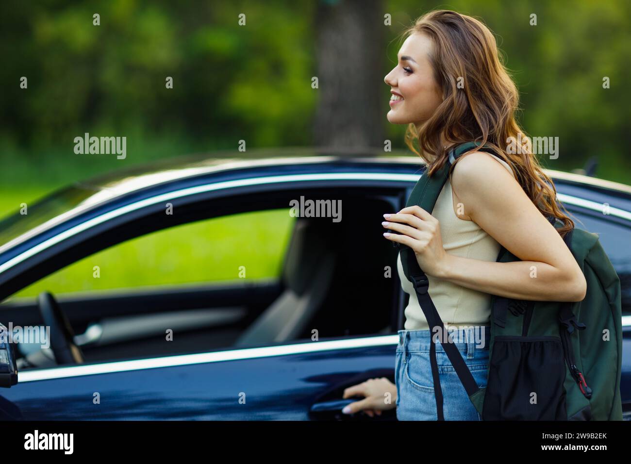 Happy woman driver gets car with backpack. Cute young happy brunette ...