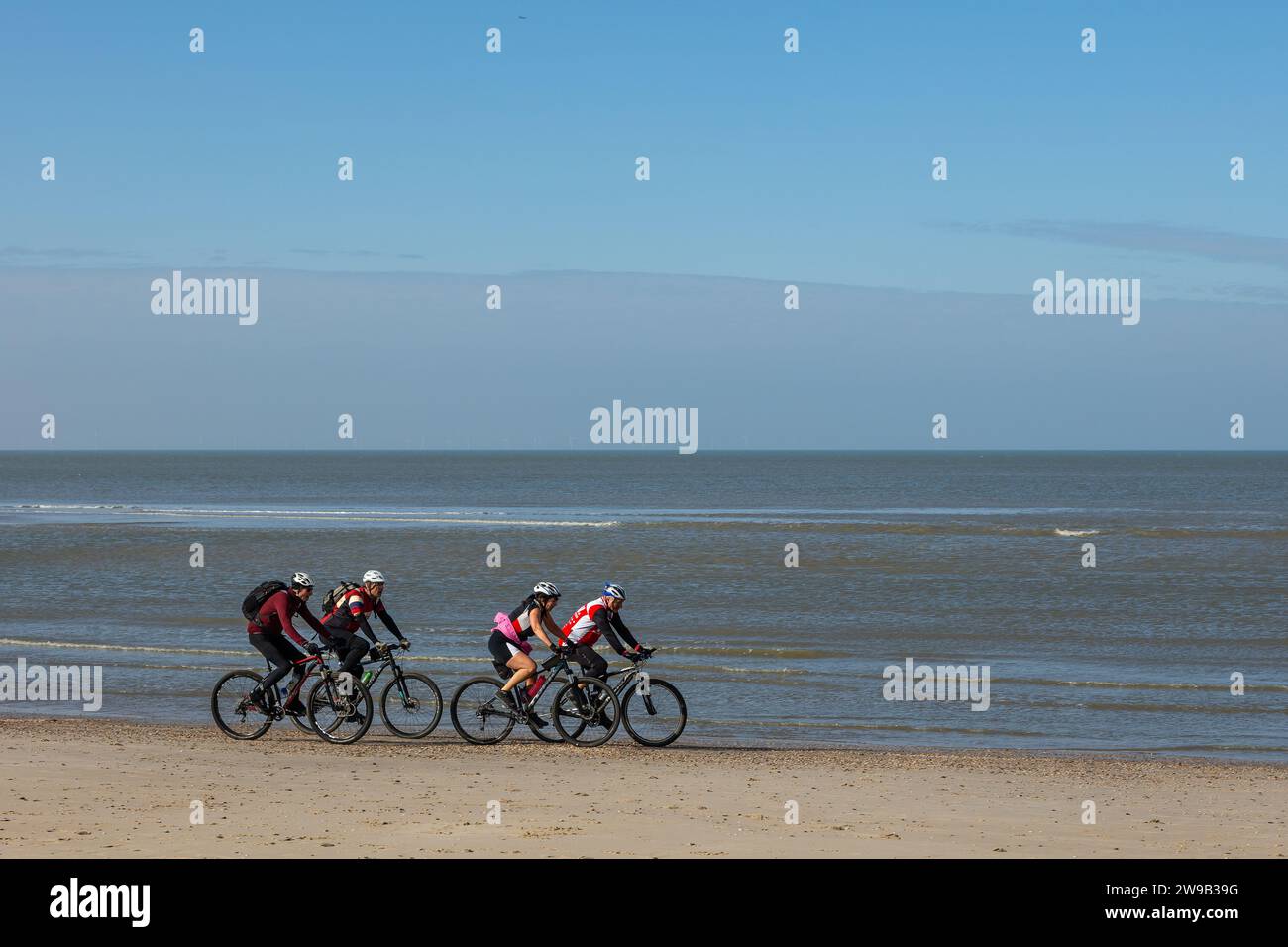 Mountain bikers riding on the beach close to the water near Egmond aan ...