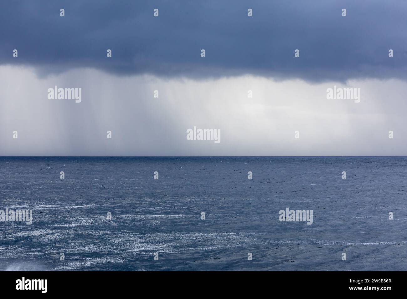 Visible rain pouring from dark clouds over the Atlantic Ocean Stock ...