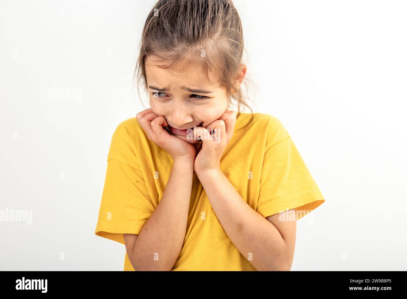 Scared and anxious girl, biting her fingernails on a white background ...