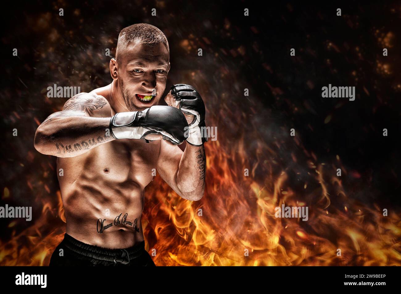 Mixed martial artist posing against the backdrop of fire and smoke ...