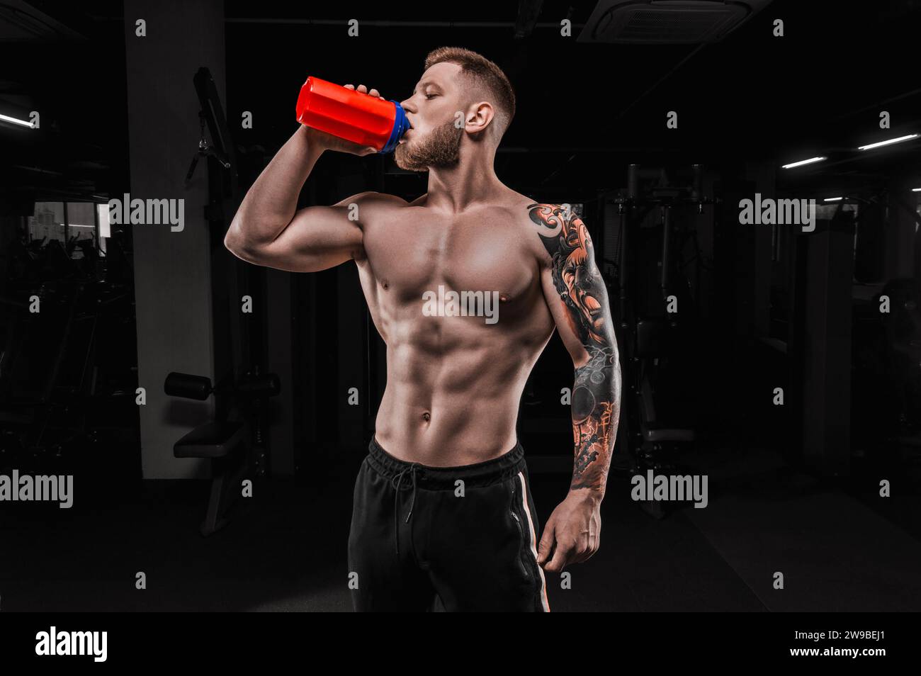 Portrait of an athlete drinking from a shaker in the gym. Bodybuilding ...