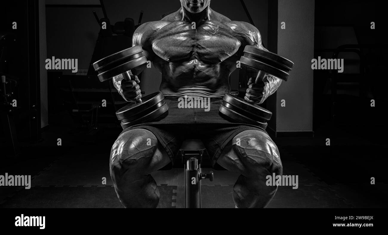 Muscular man sits on a bench with dumbbells. Bodybuilding and ...