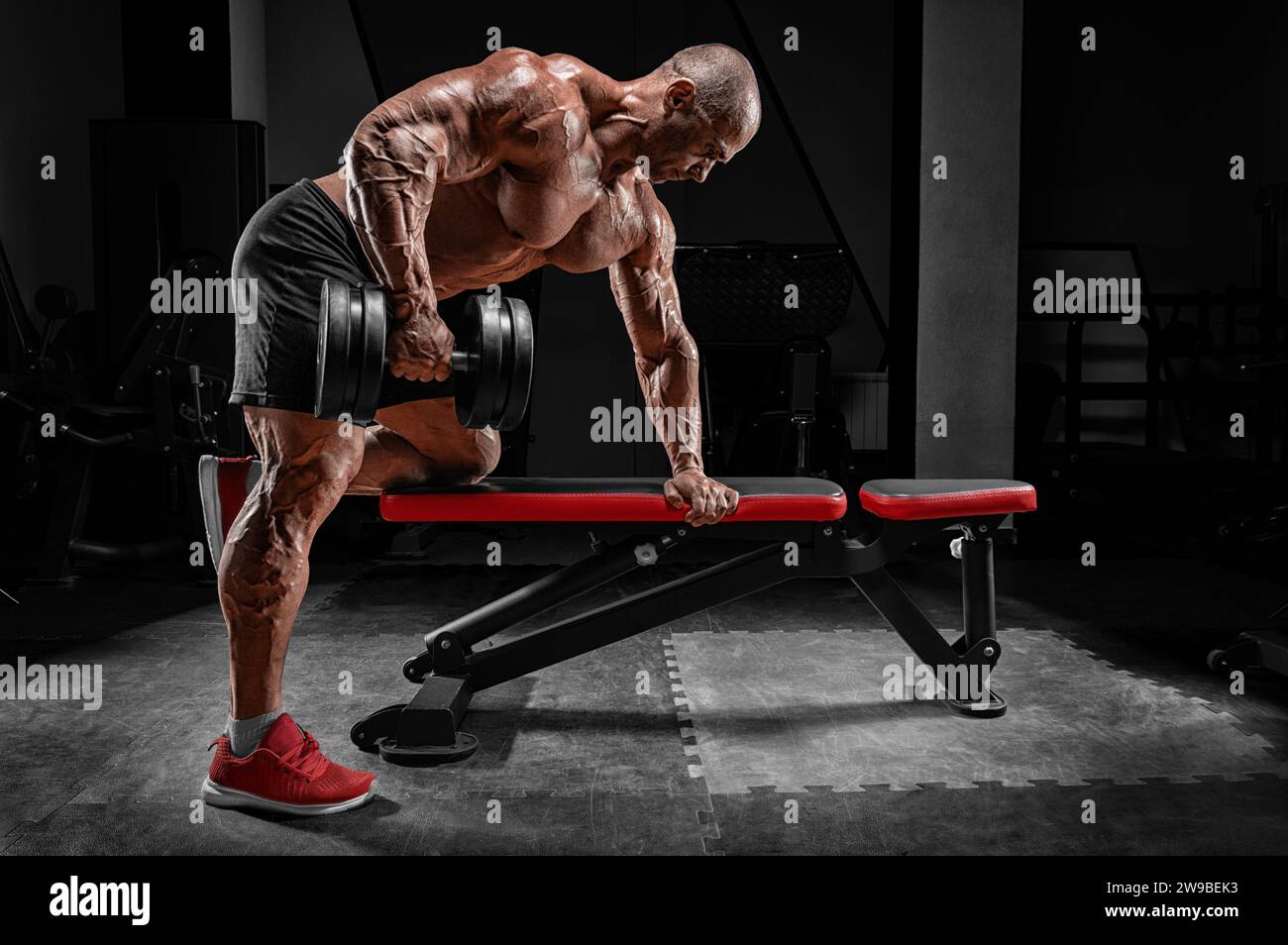 Muscular man pulls a dumbbell towards his stomach. Bodybuilding and ...