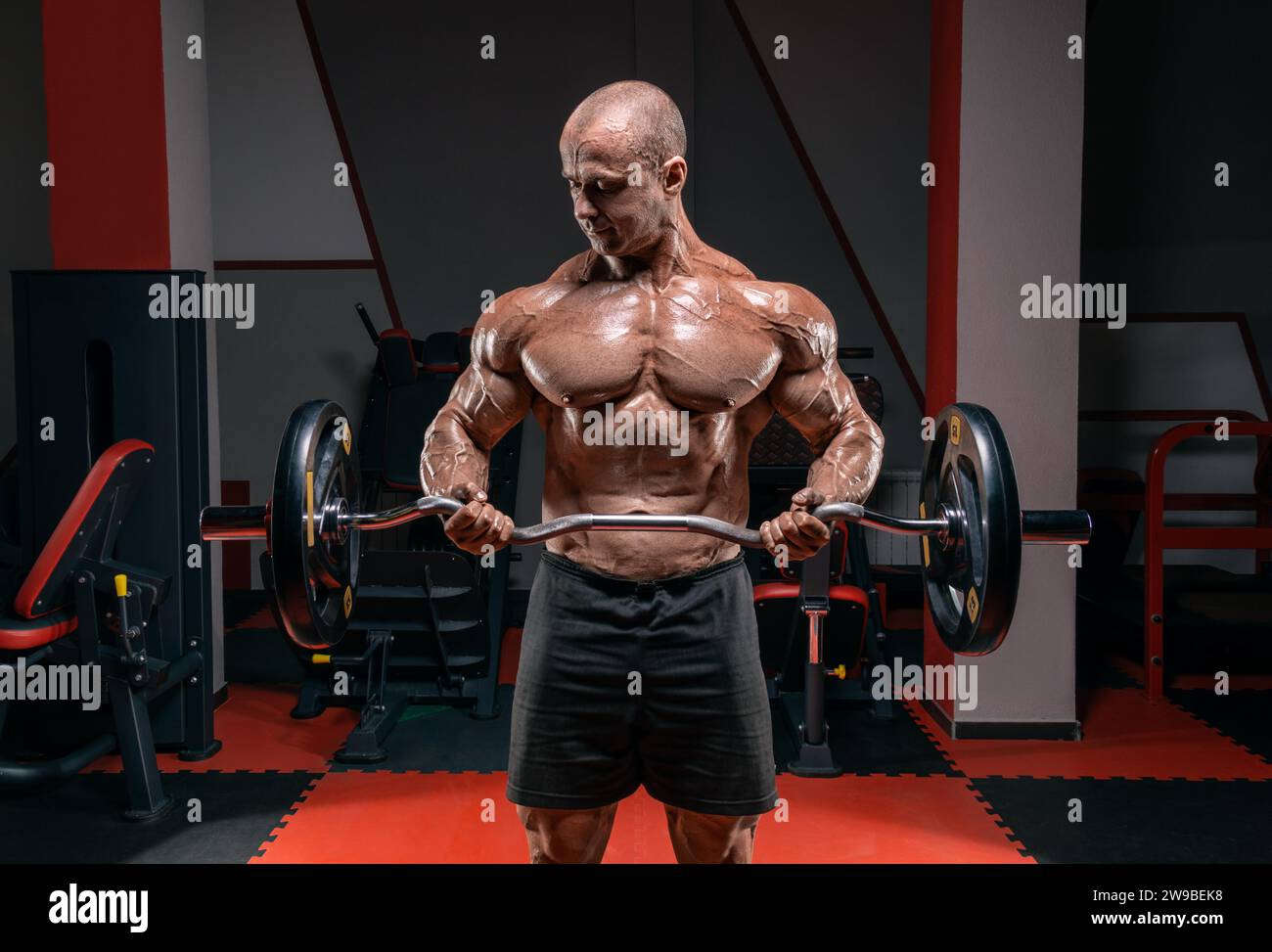 Powerful bodybuilder posing in the gym with a barbell. Bodybuilding ...