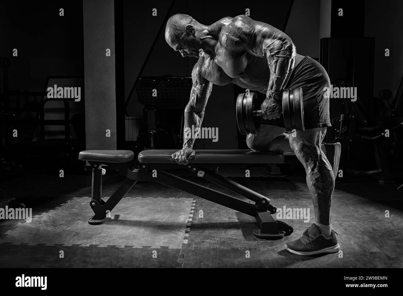 Muscular man pulls a dumbbell towards his stomach. Bodybuilding and ...