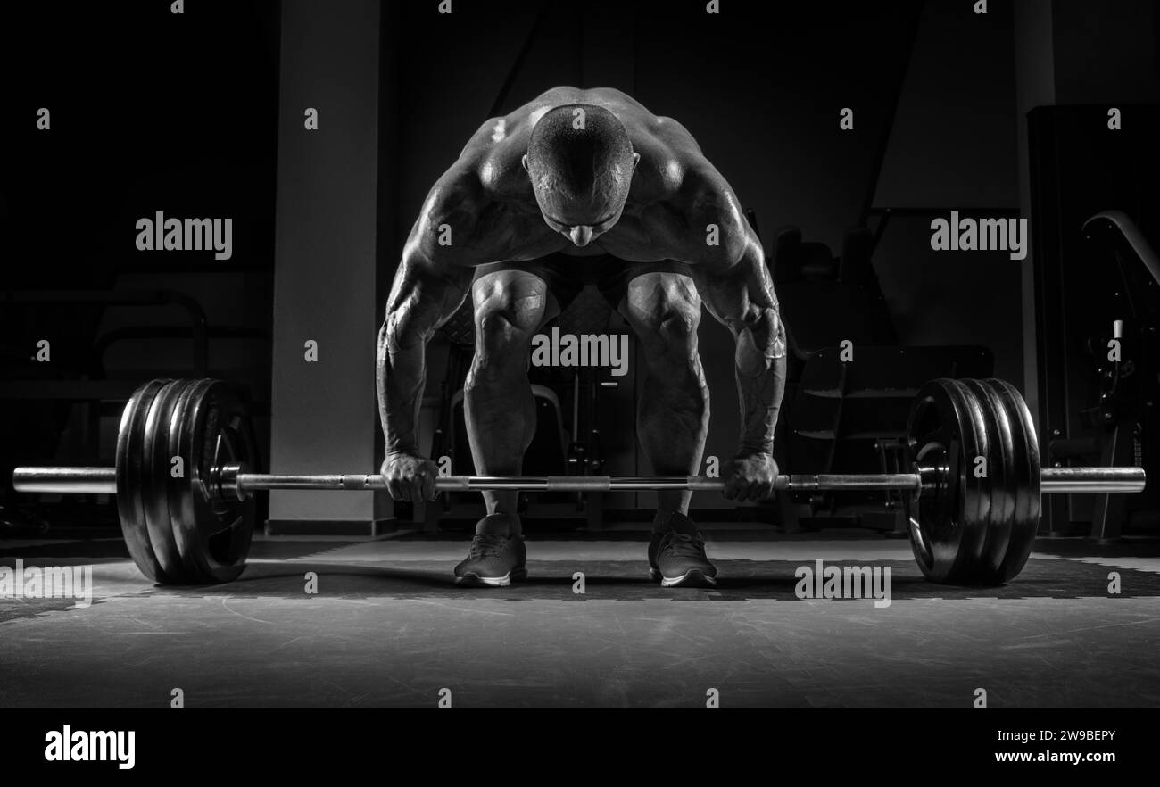 Muscular man is unbending with a barbell in his hands. Deadlift ...