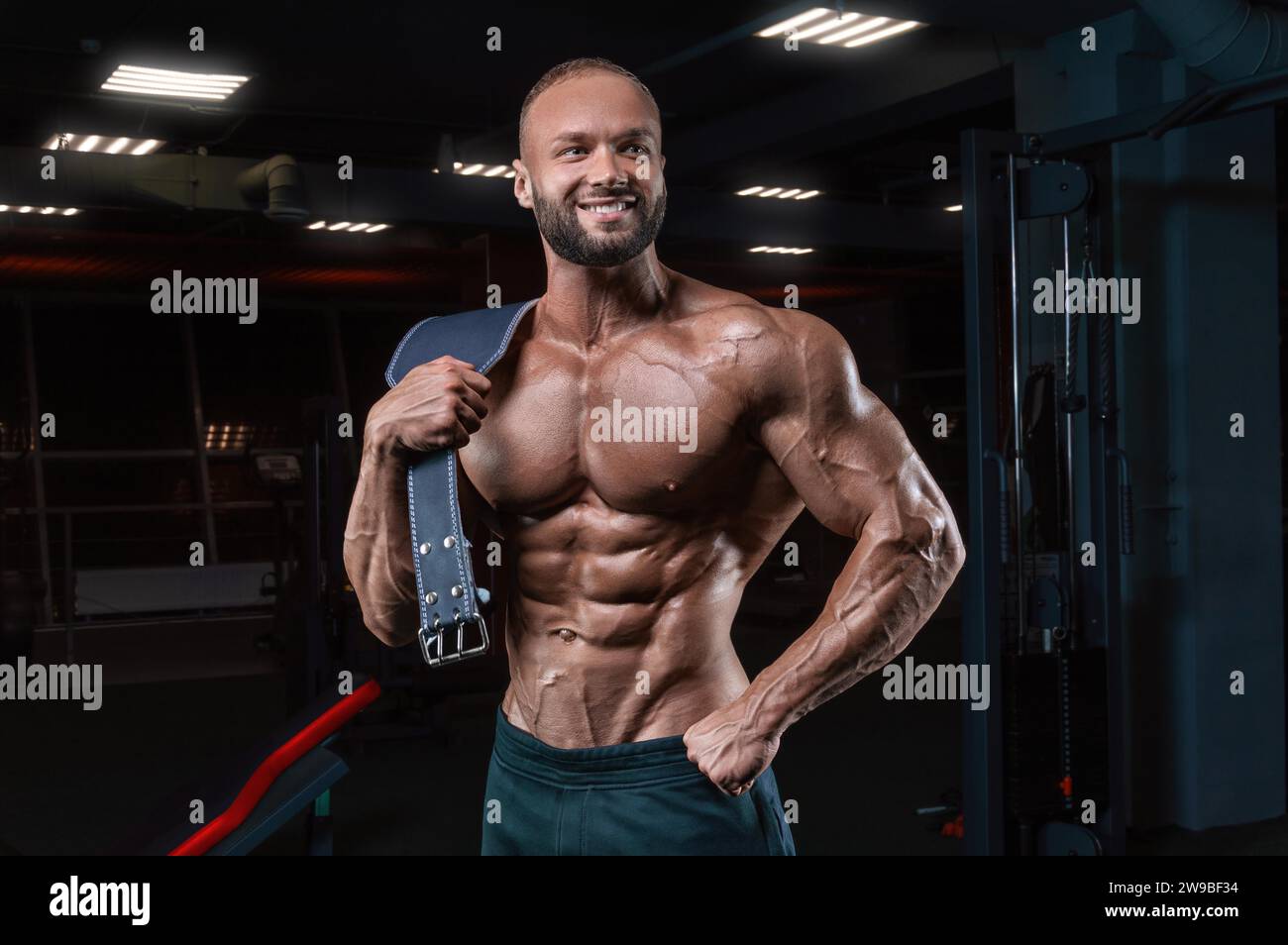 Muscular man poses in the gym with an athletic belt. Sports ...