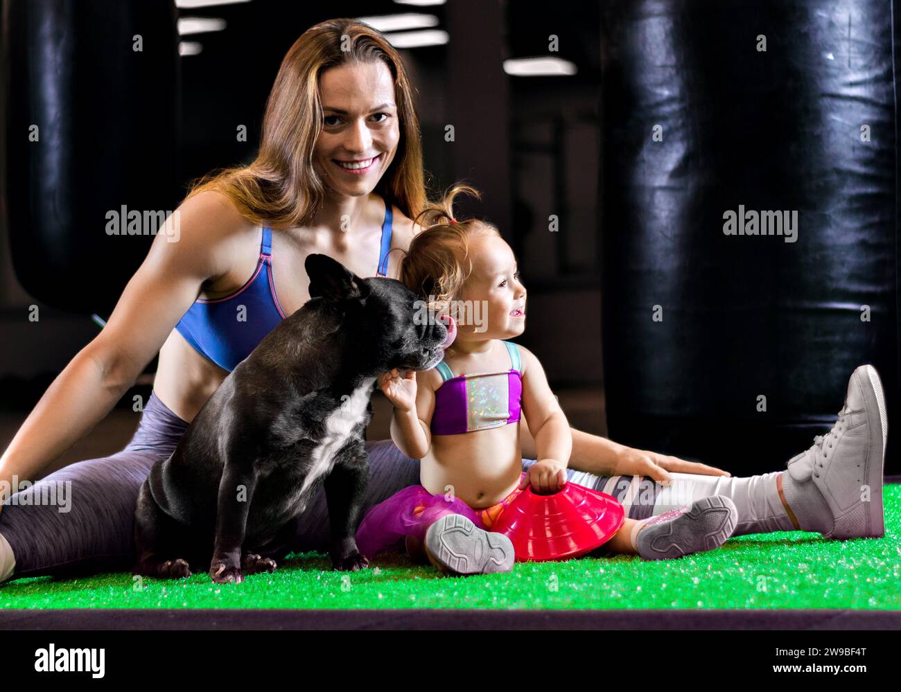 Charming sports mom trains in the gym with her little daughter and a ...