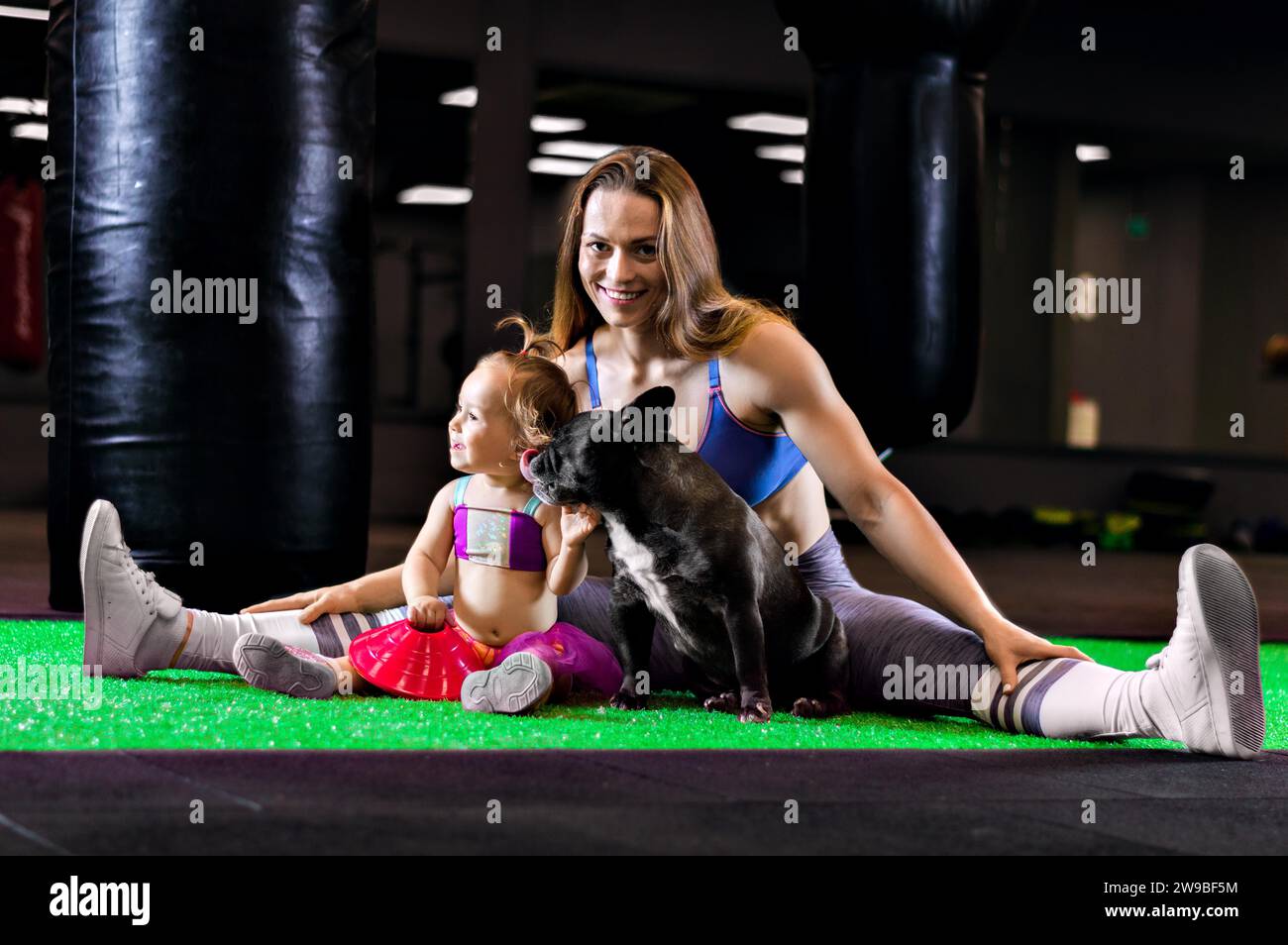 Charming sports mom trains in the gym with her little daughter and a ...