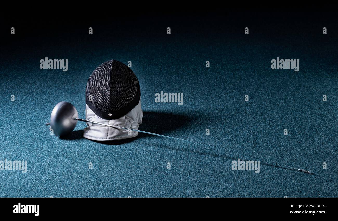 The sword and mask lie on a blue background. The concept of fencing ...