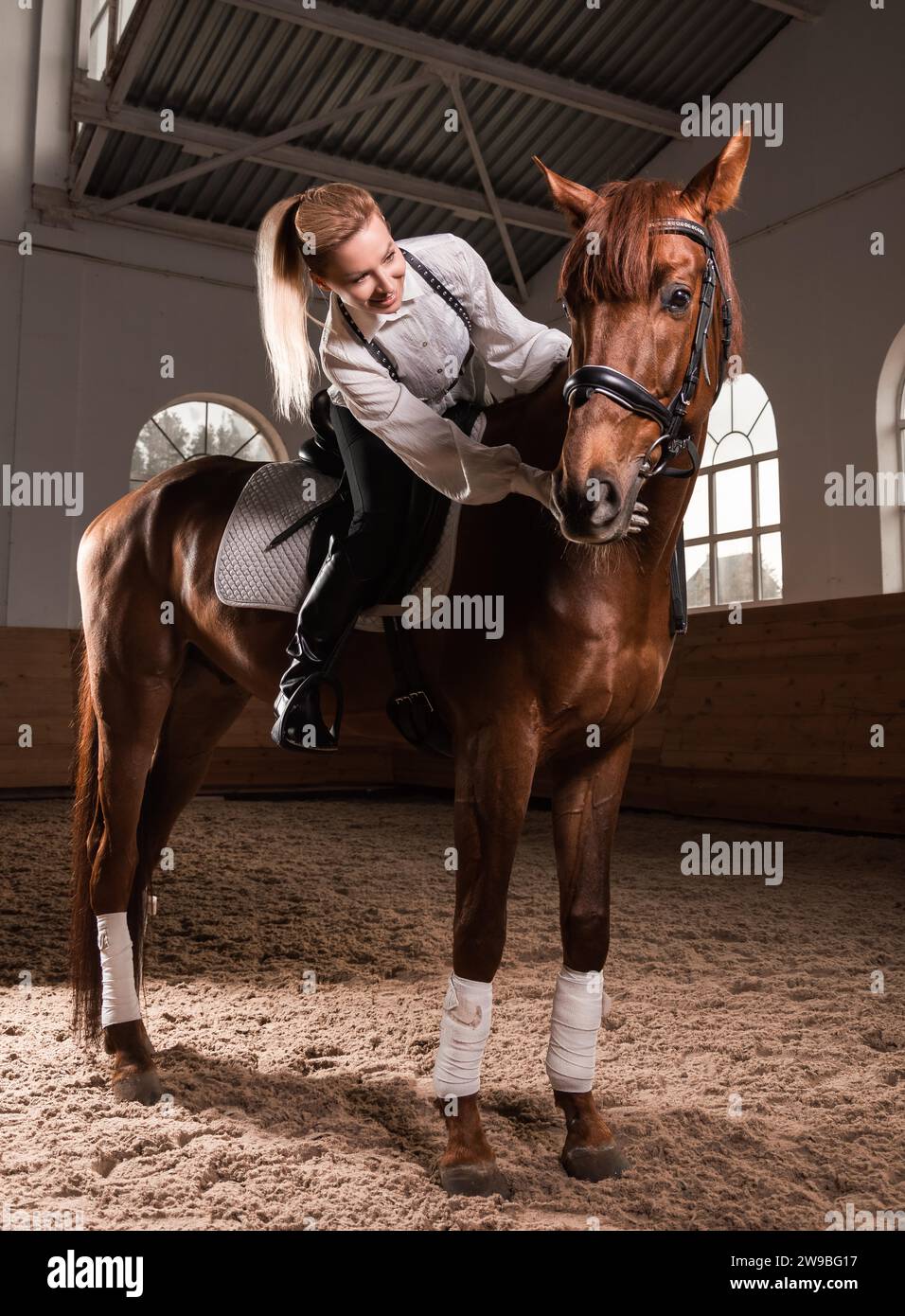 Image of a woman riding a thoroughbred horse. The background is a ...
